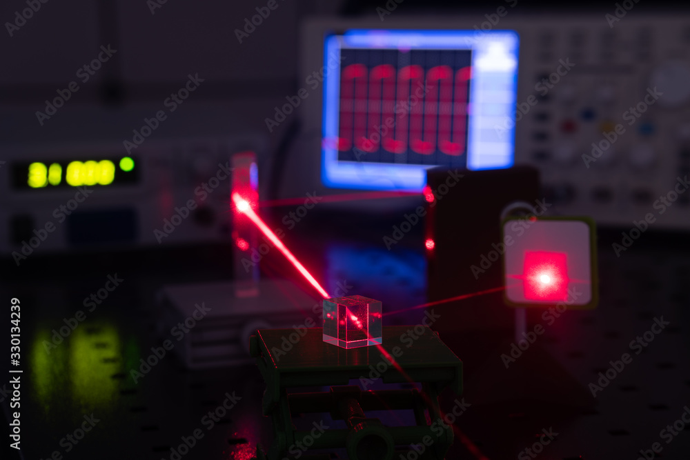 Experiment in optic lab with laser device. Red laser on optical table ...