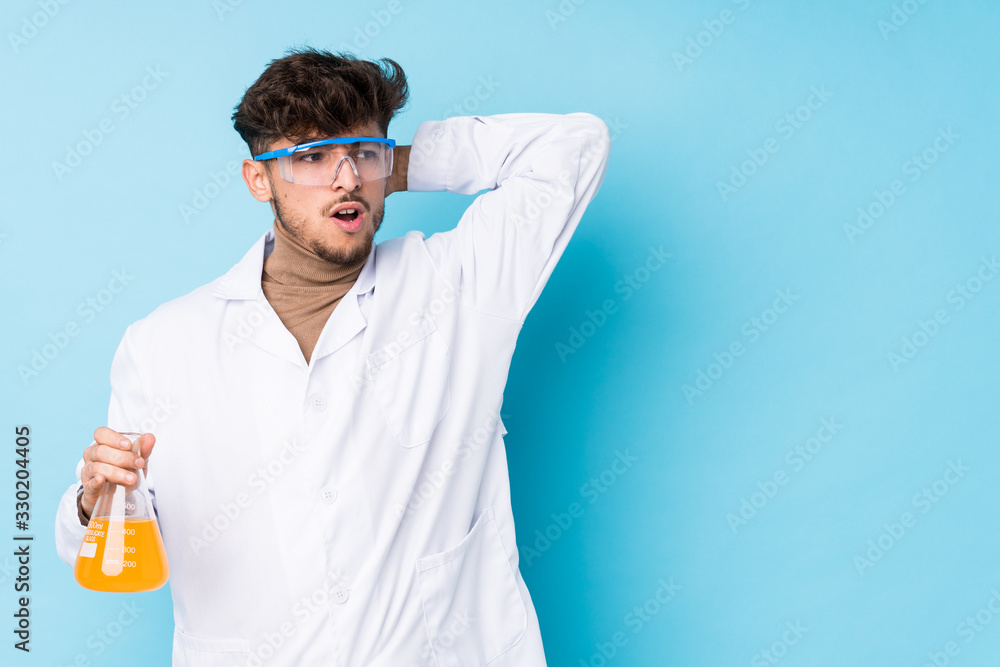 Young arab scientific man isolated touching back of head, thinking and ...