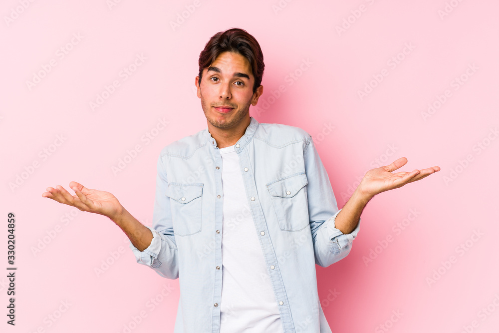 Young caucasian man posing in a pink background isolated doubting and ...