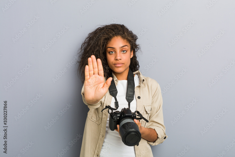 Young african american photographer woman holding a camera standing ...