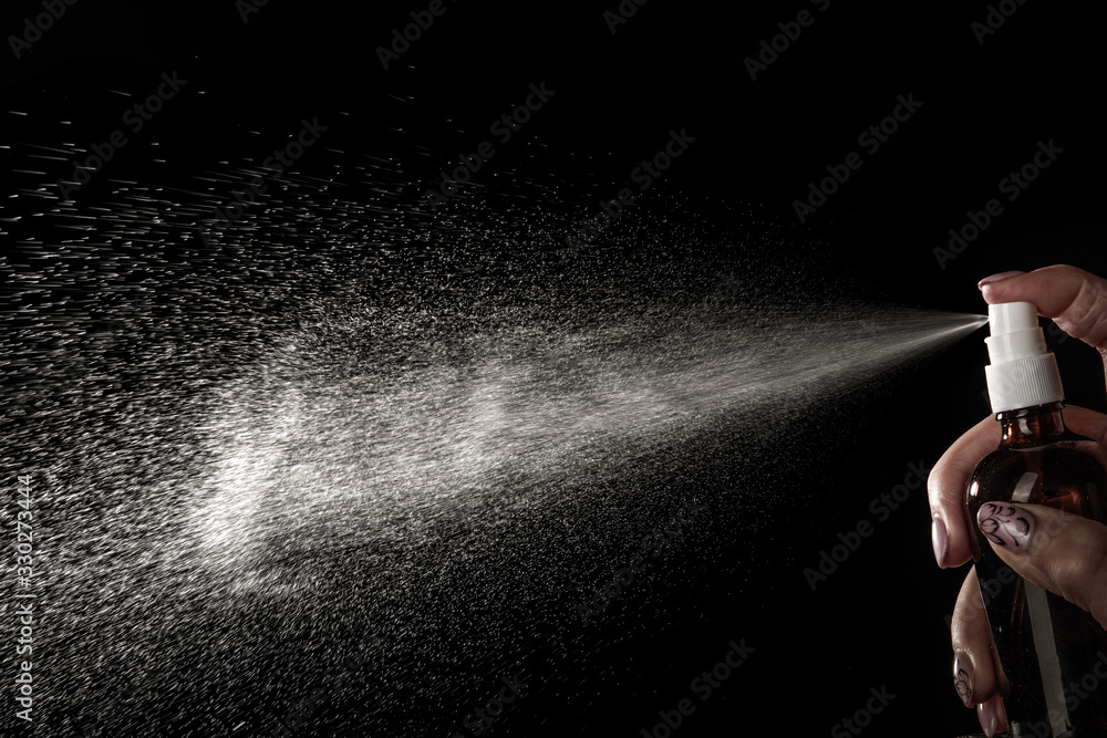 The hand presses the button of the aerosol dispenser. Water jet on a ...
