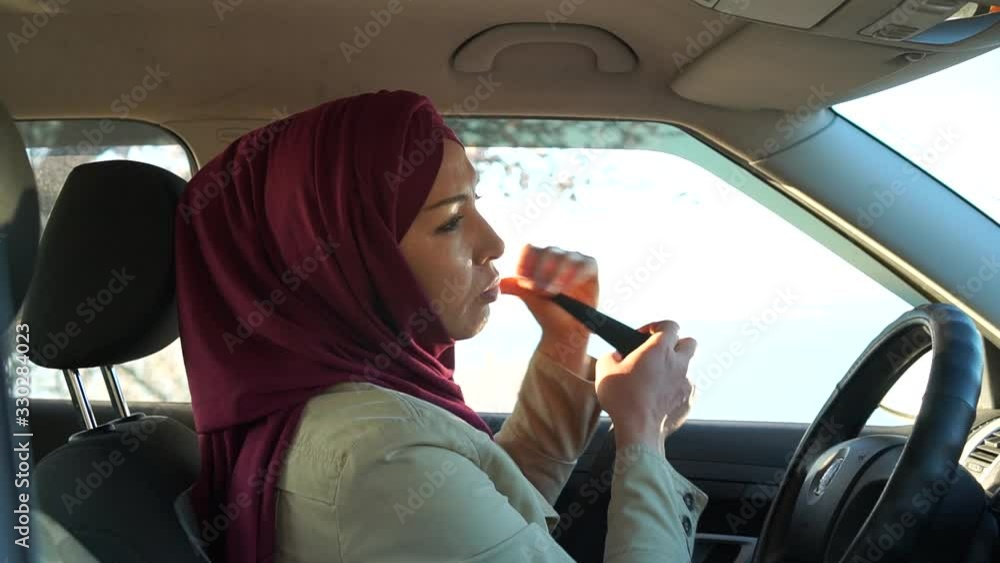 Arab lady driving car. A modern Saudi Muslim business woman fastens her ...