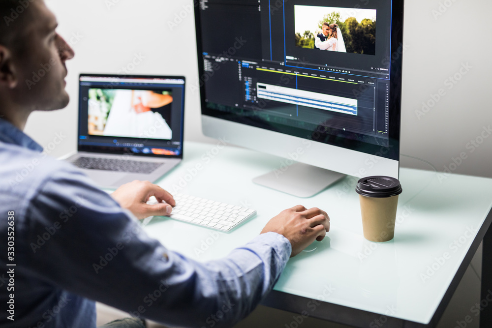 Young man video editor with works with footage on his personal computer ...