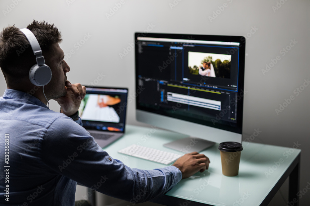 back view of video editor using computer working with fotoage at his ...