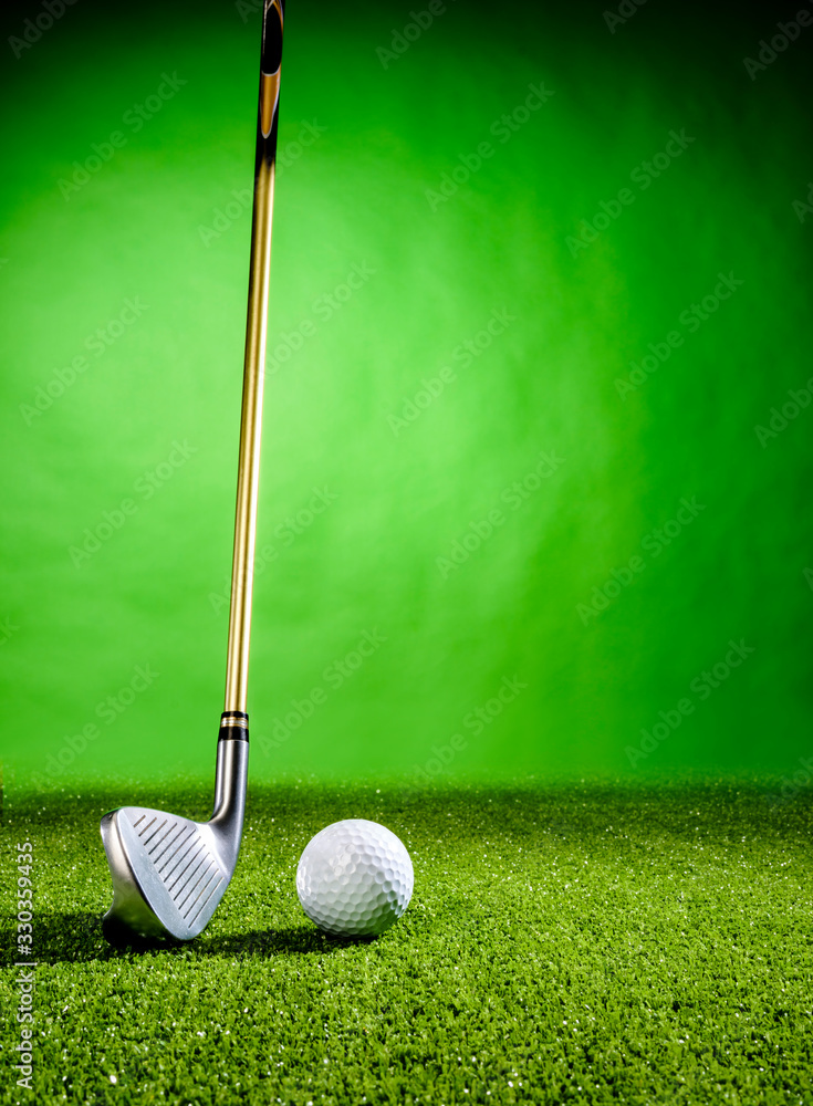 Golf club and golf ball on the turf with green wall in the background ...