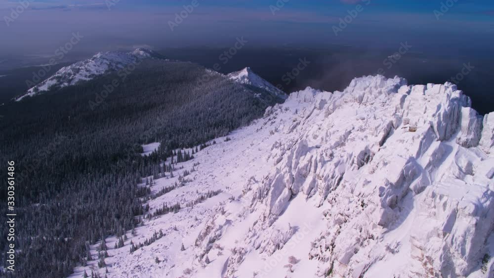 Epic aerial flight over mountain range in winter. Trees and mountain ...