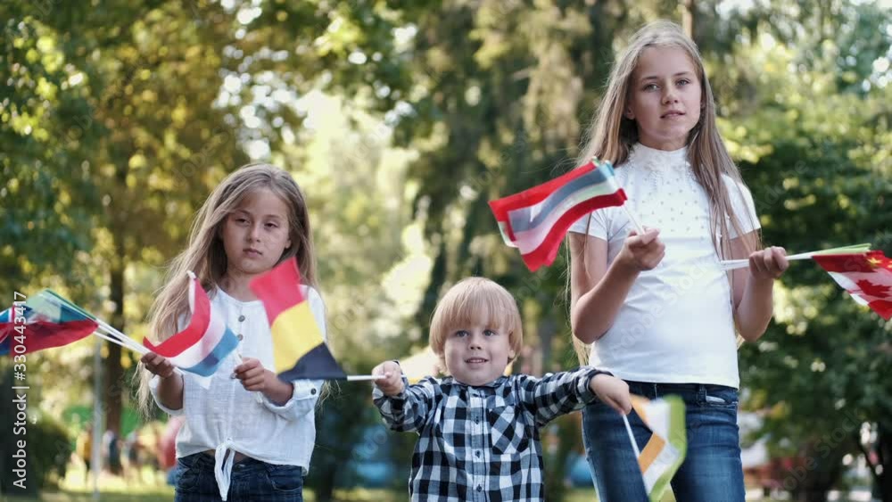 Kids spend time outside in summer. Children are holding flags. Kids ...