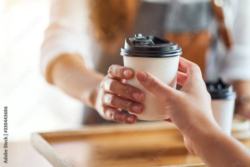 A waitress holding and serving paper cups of hot coffee to customer in ...