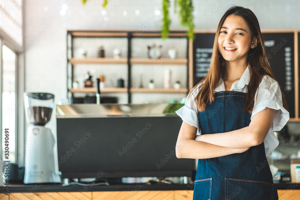 Pretty young asian waitress standing arms crossed in cafeteria.Coffee ...