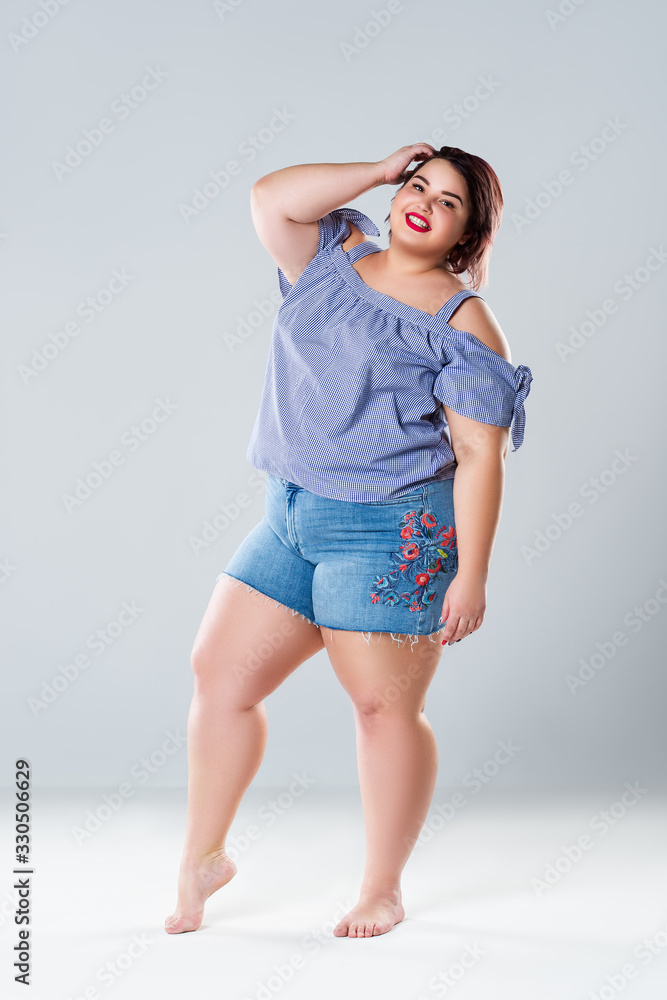 Plus size fashion model in jean shorts, fat woman on gray background ...