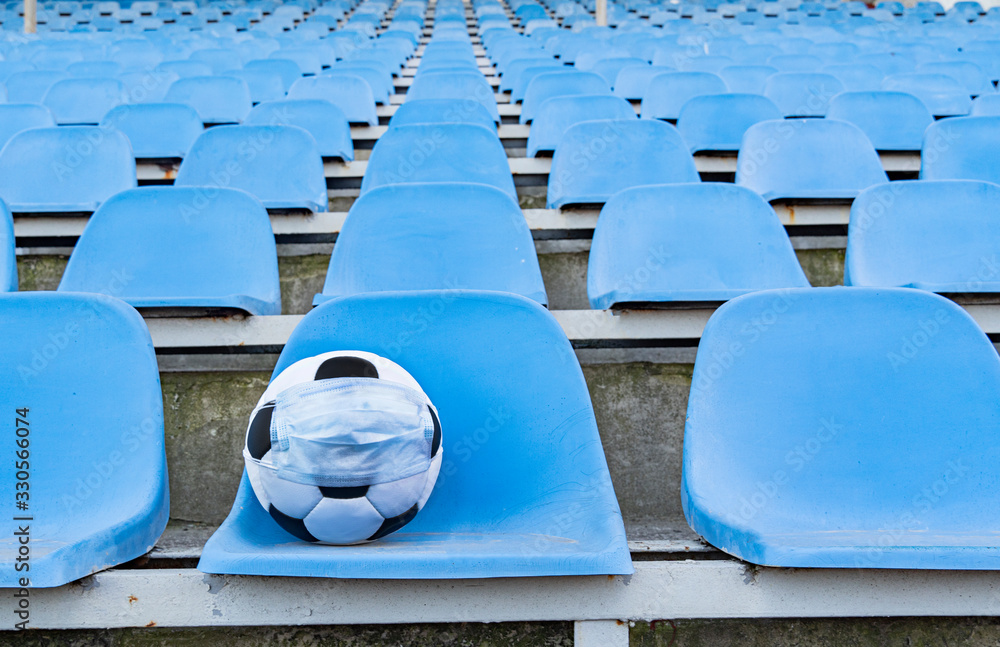 Soccer ball in a medical mask on the background of empty stands ...