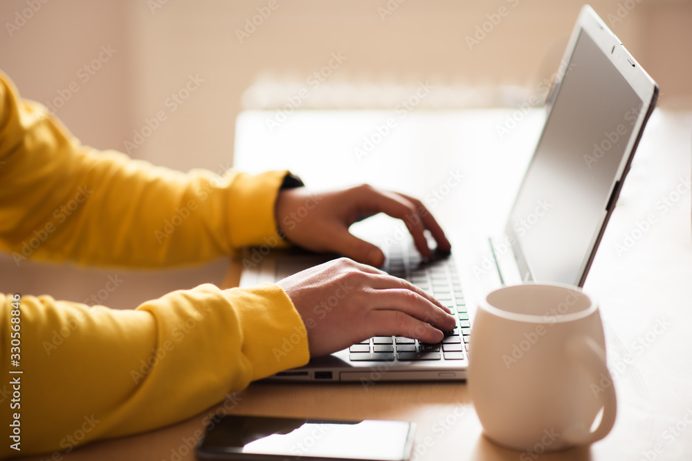 Man hand in yellow sweatshirt typing on laptop computer keyboard at ...