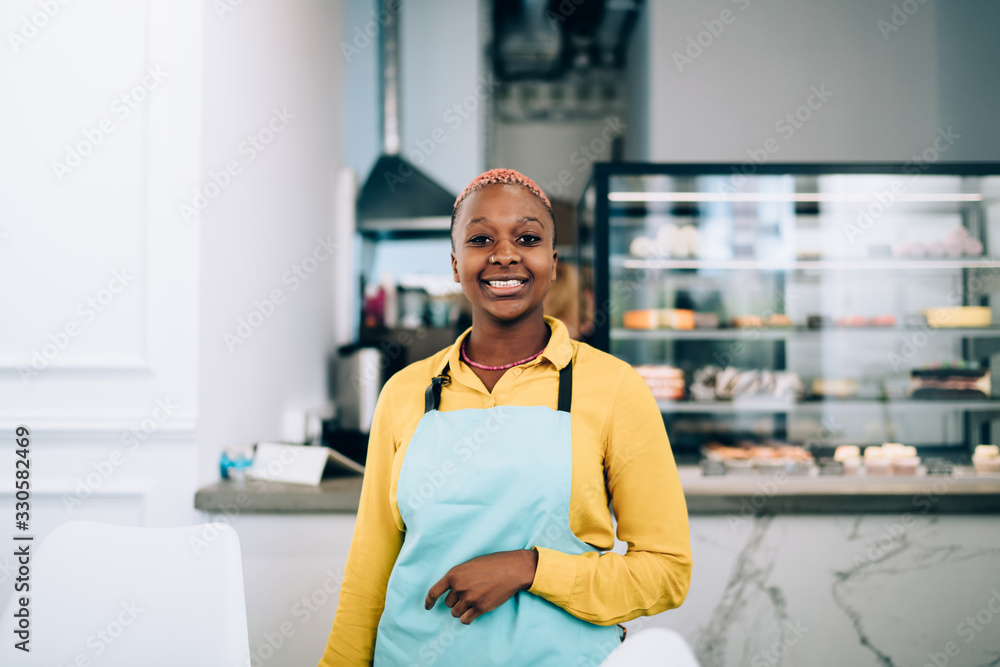 Happy ethnic adult self employed woman against blurred counter and ...
