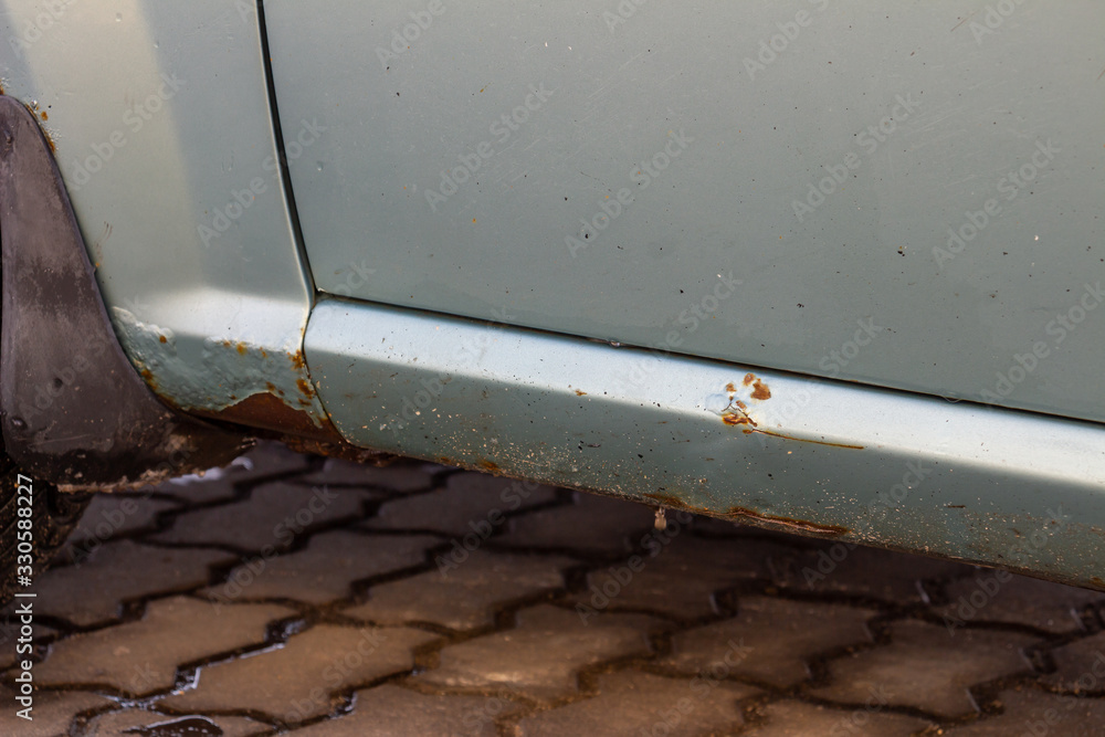 Rust on the body of a blue car. Rust hole on old worn painted metal ...