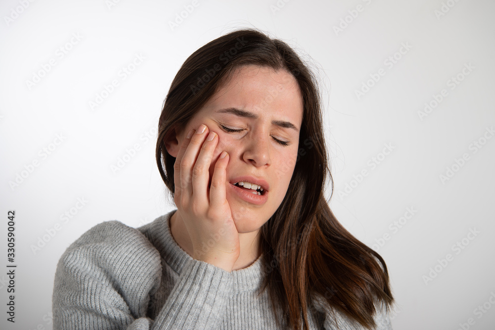 Painful facial expression of a young woman with tooth ache holding her ...
