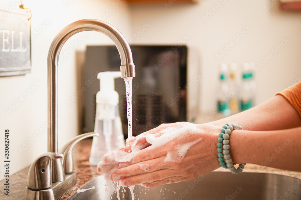 Woman washing hands with hot soapy water to prevent germs and illness ...