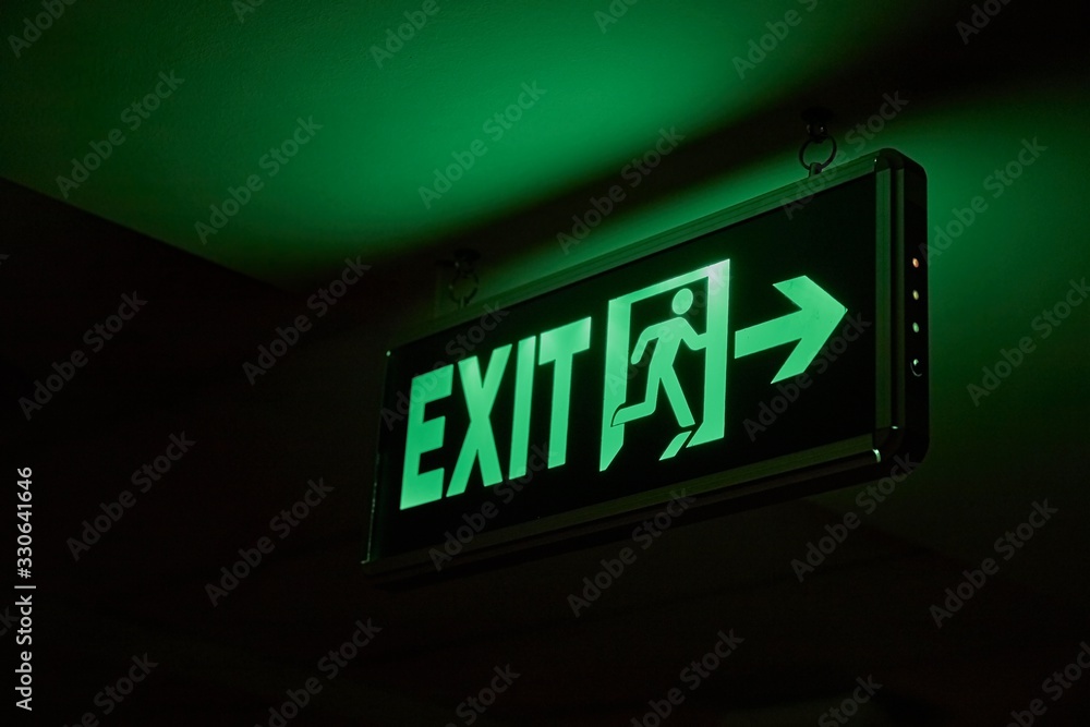 Emergency exit sign glowing in the dark Stock Photo | Adobe Stock