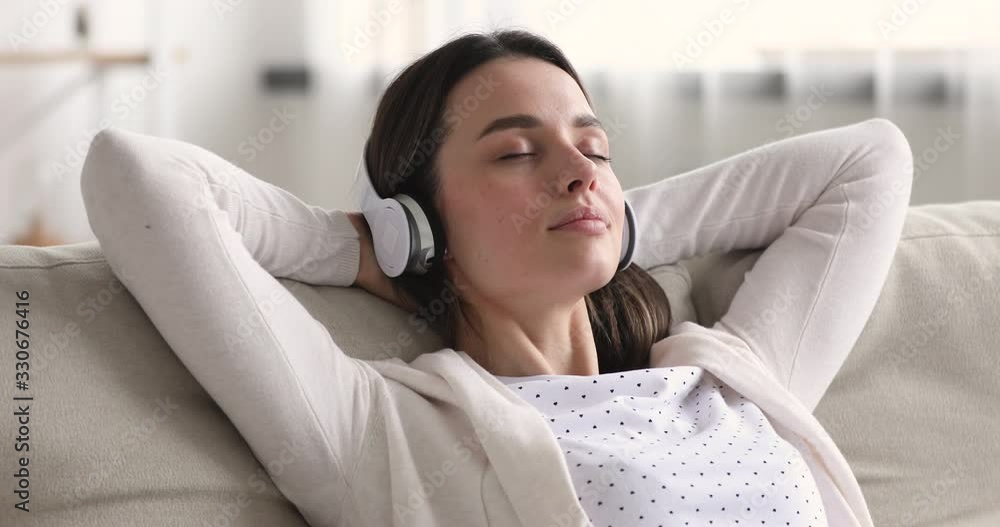 Calm relaxed young woman chilling on couch with eyes closed wearing ...