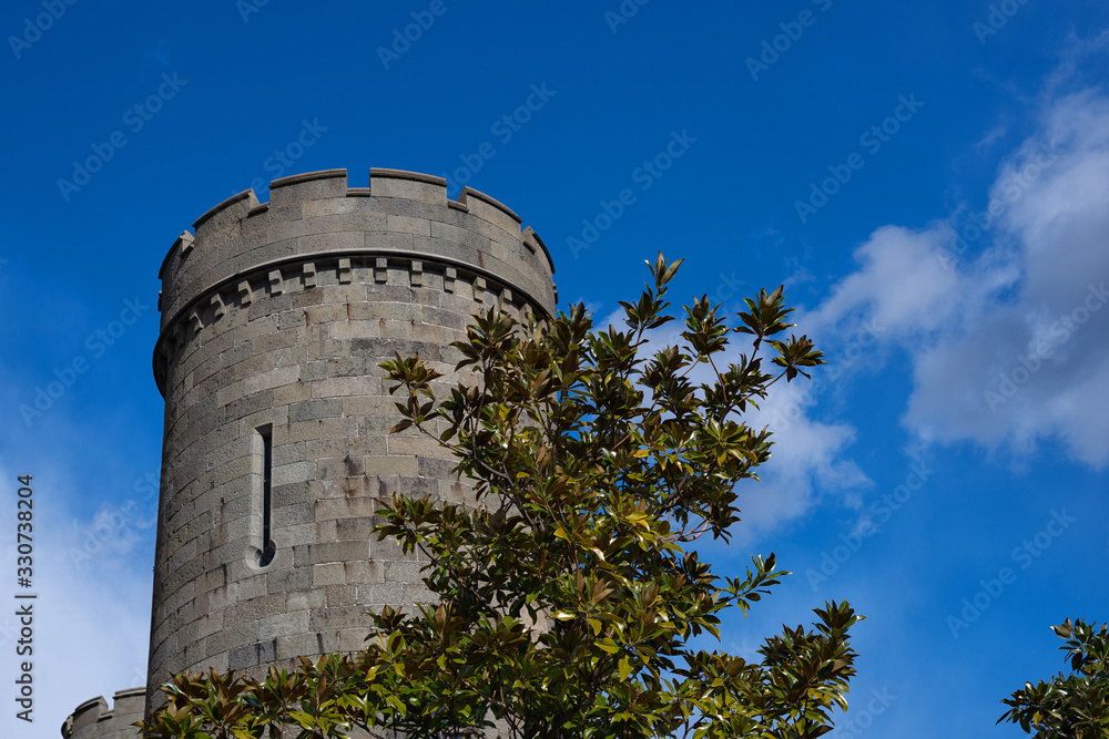 Ancient round stone tower with battlements with blue sky and white ...