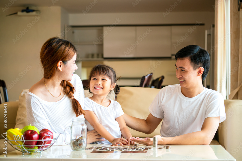 Asian family teaching their daughter saving money to piggy bank for her ...