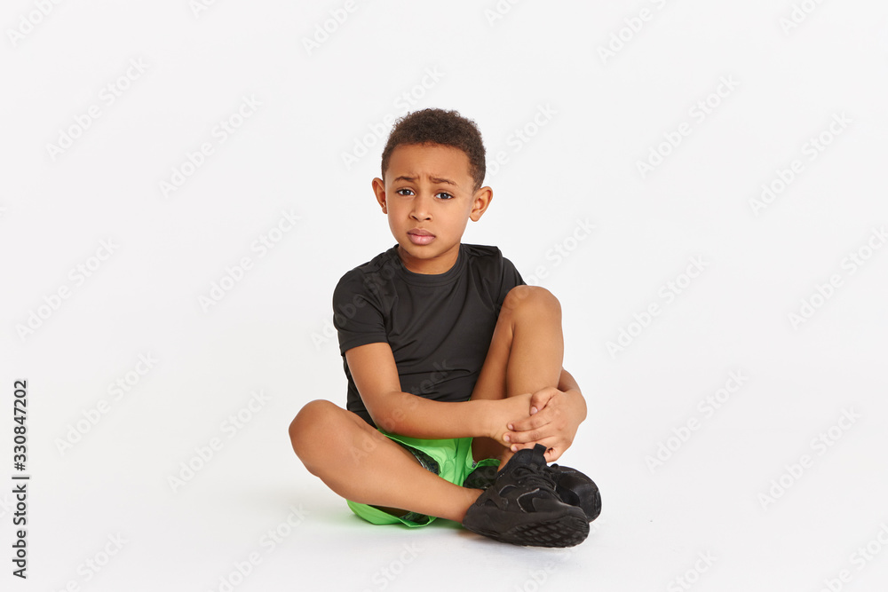 People, sports and injury concept. Picture of sad upset African little ...