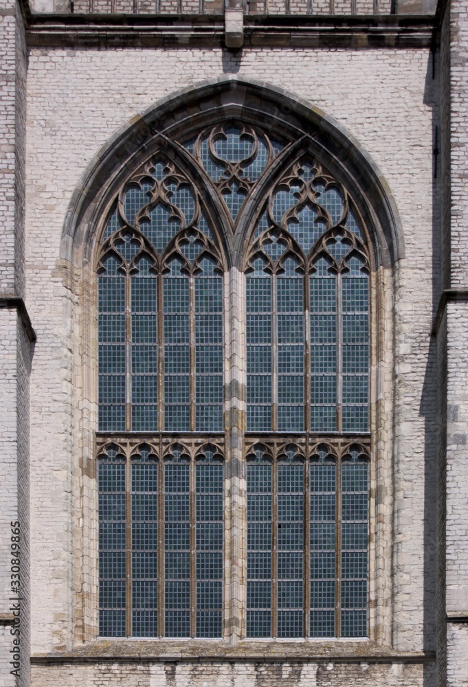 Pointed ogive arch with gothic window at the facade of Goes city church ...