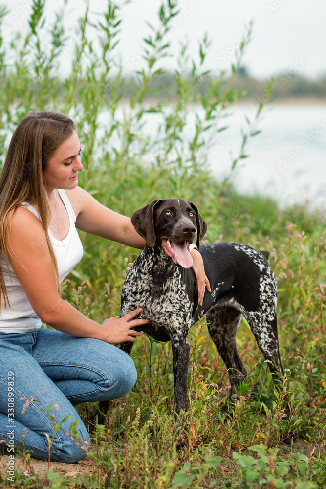 Woman walking her dog and both explore the terrain together in playful ...
