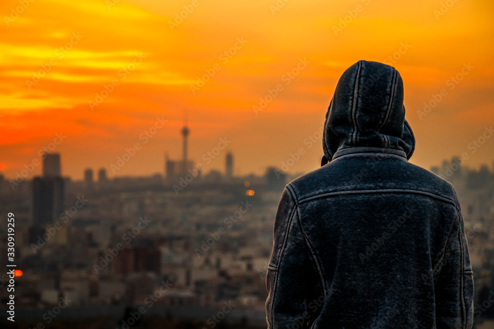 Moody portrait with Tehran skyline at the background. Alone man looking at cityscape of Tehran ...