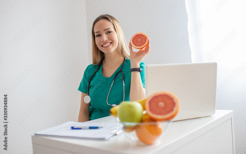 Female nutritionist with fruits working at her desk. Smiling ...