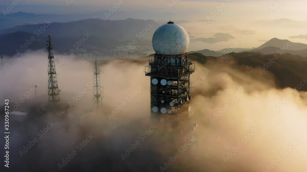 Telecommunication radar antenna tower standing over clouds on the top of mountains with ...