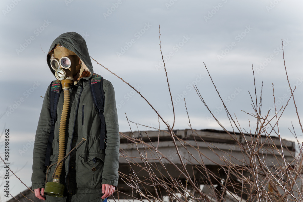 Human in gas mask standing among ruins and dramatic sky background ...