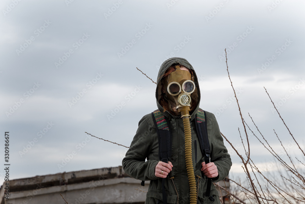 Human in gas mask standing among ruins and dramatic sky background ...