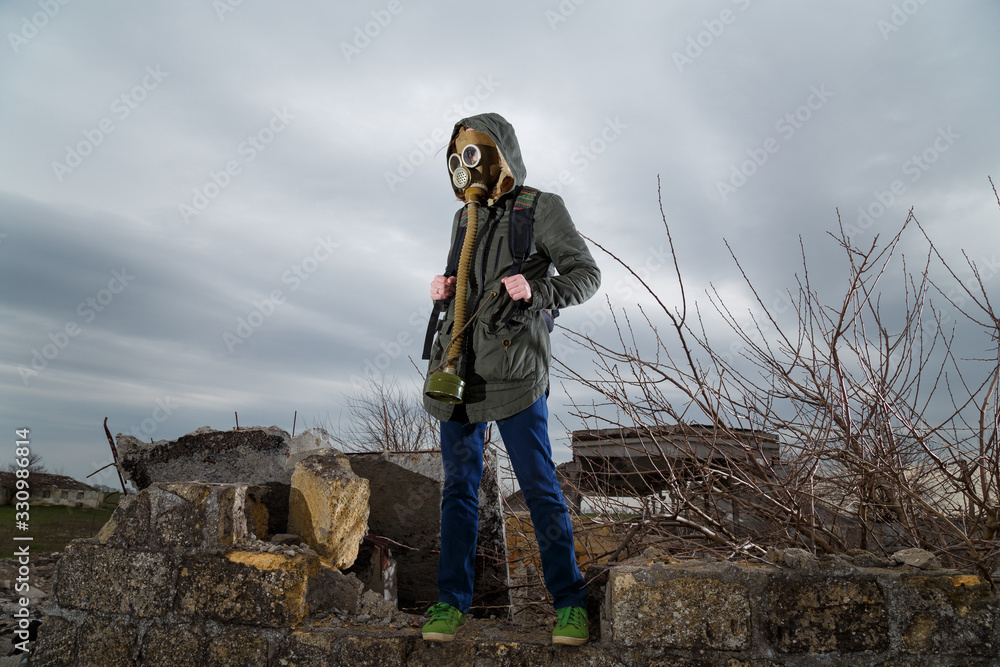 Human in gas mask standing among ruins and dramatic sky background ...