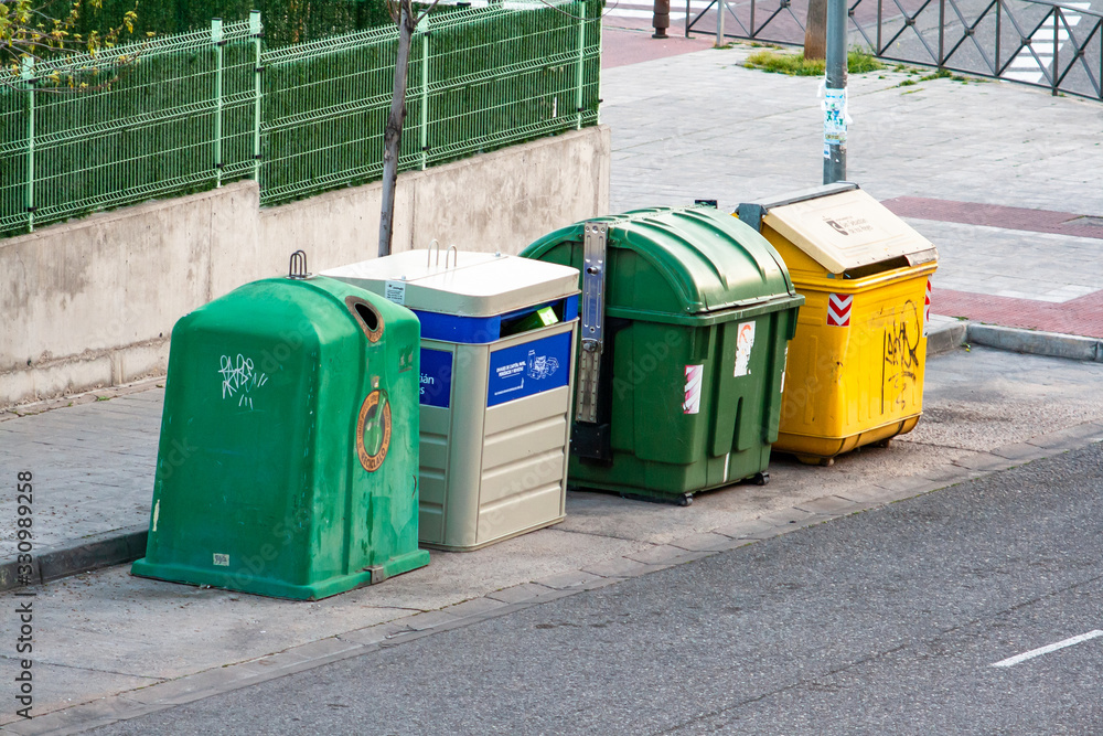 Four types of waste collection and recycling containers on the sidewalk ...