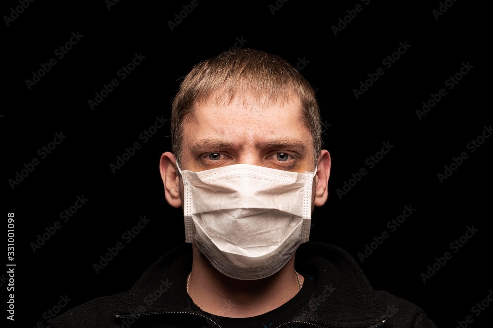 A sick male patient in a protective medical anti-bacterial mask looks ...