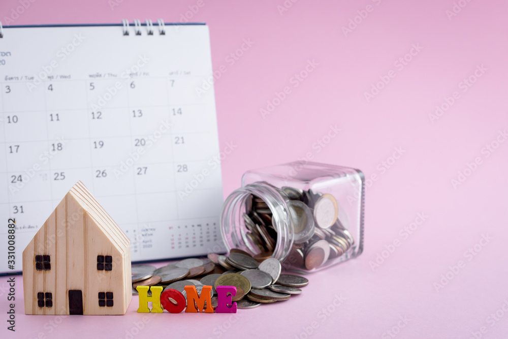 Wooden house model with HOME alphabet, money coins in the glass jar and ...
