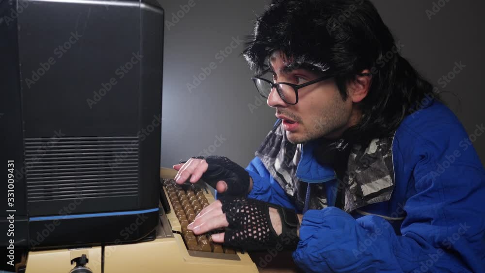 Concentrated retro nerd in glasses from the 70s 80s, typing while using ...
