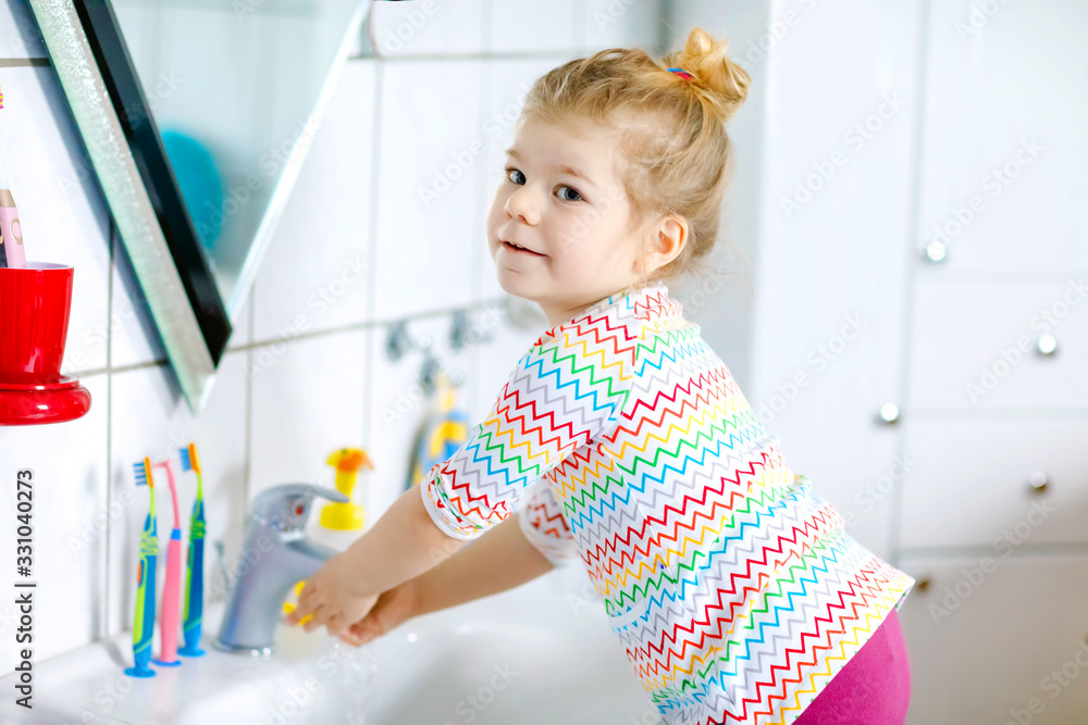 Cute little toddler girl washing hands with soap and water in bathroom ...