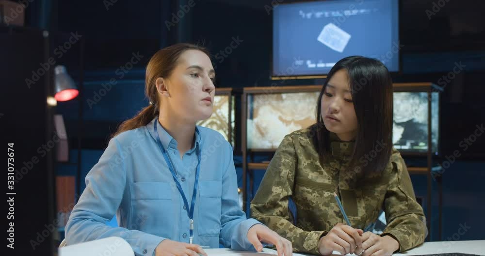 Female Caucasian office worker and soldier sitting together at desk in ...