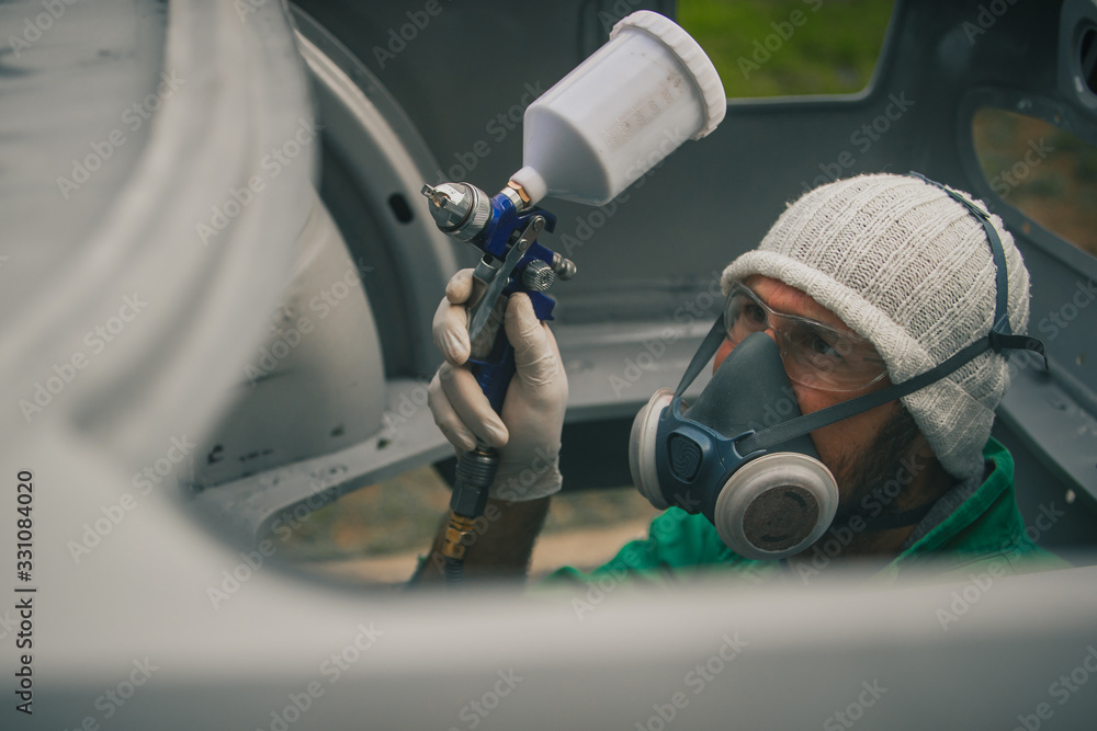 Caucasian man is spraying color with a compressed air paint gun on the ...