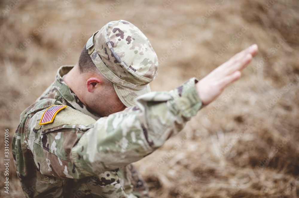 Selective focus shot of an American soldier with his hand raised above ...