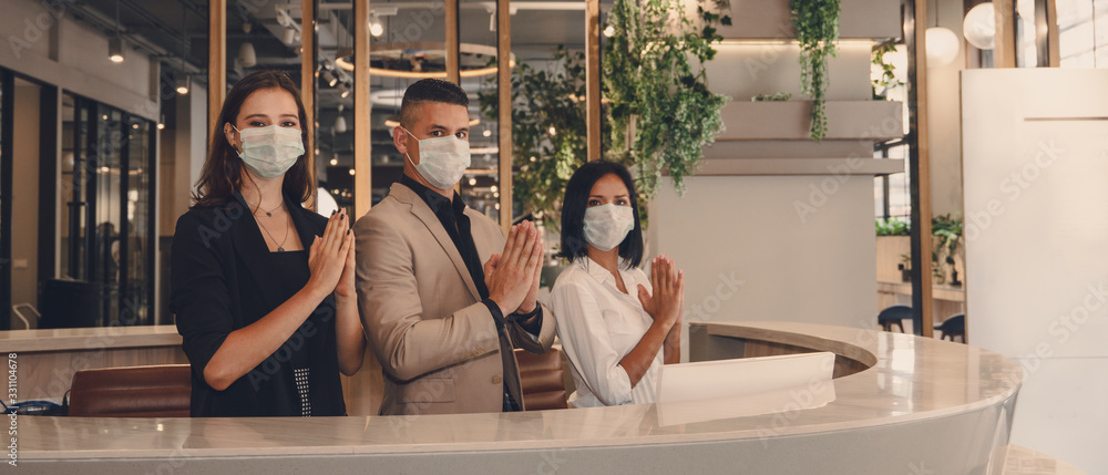 hotel receptionist wearing medical mask and show greeting with thai wai ...