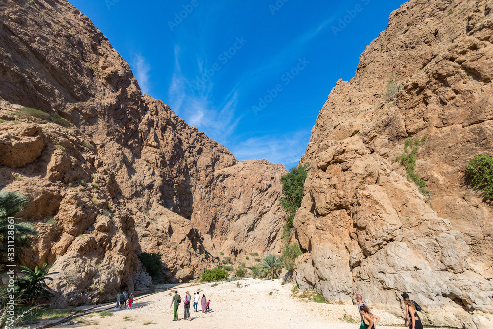 Wadi Shab river canyon with rocky cliffs and green water springs ...