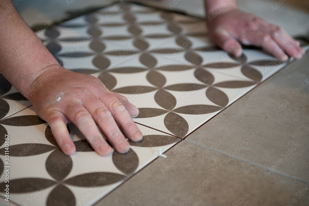 Tiler laying the ceramic tile on the floor. Professional worker makes ...