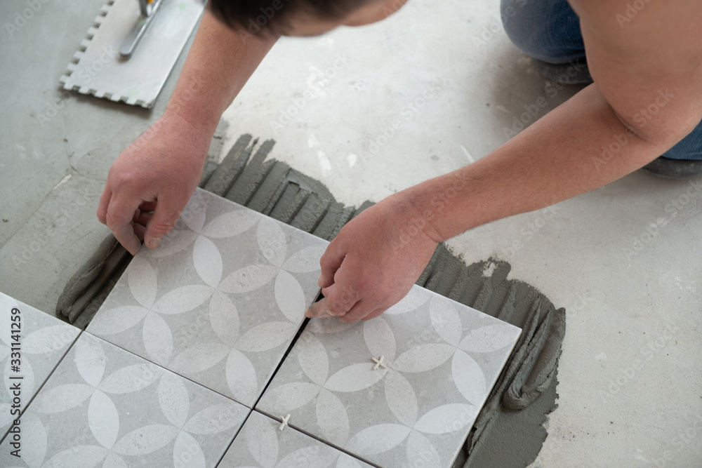 Tiler laying the ceramic tile on the floor. Professional worker makes ...