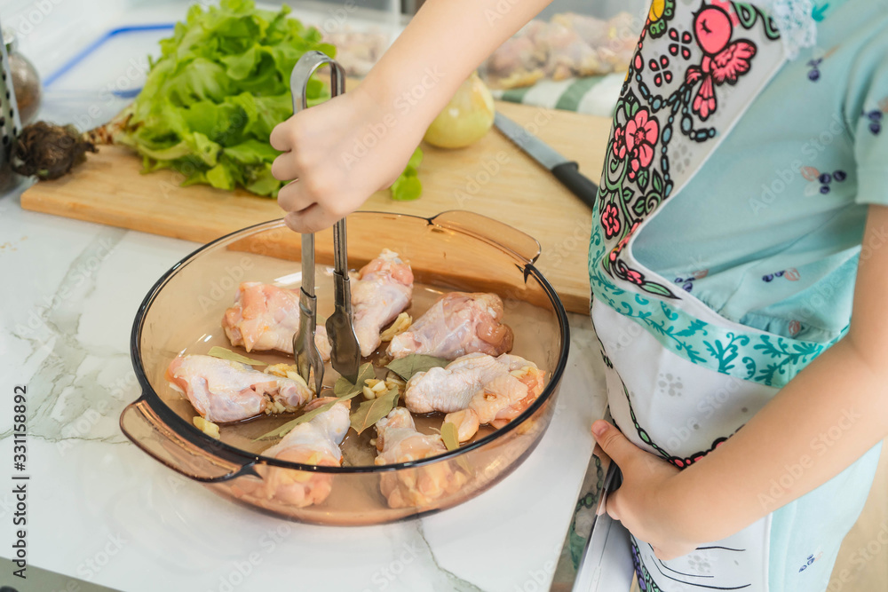 little girl cook with chicken in kitchen. Happy little girl cook with ...