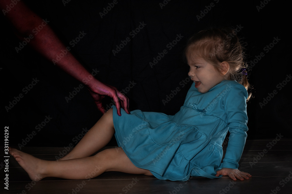 a little girl sits on the floor in a dark room, a terrifying scary ...