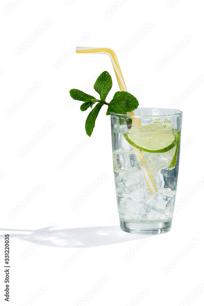 Mojito cocktail with ice cubes is contained in a highball glass with a straw, lime slices and a ...