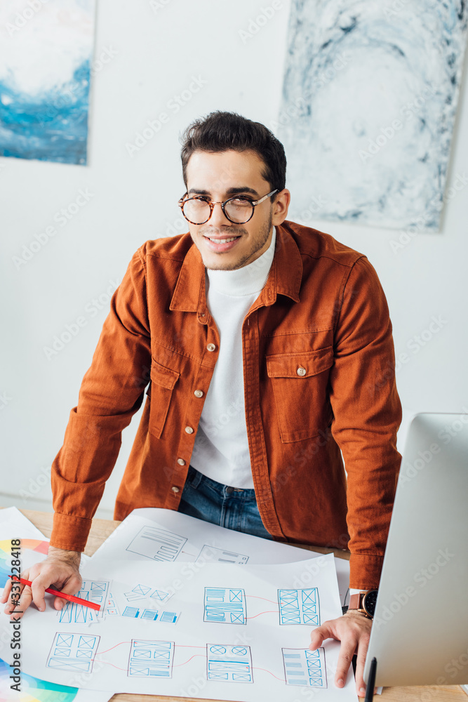 Handsome ux designer smiling at camera while working with website ...