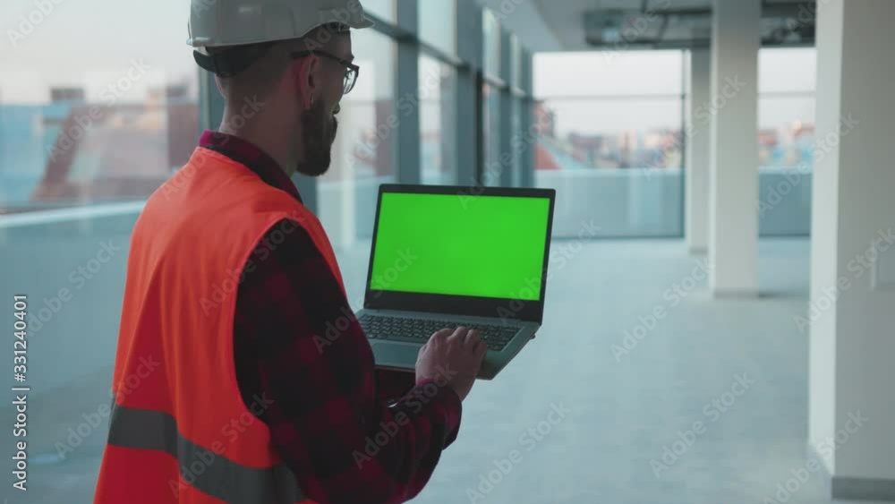 Shot back of man engineer stand using laptop computer with green screen ...